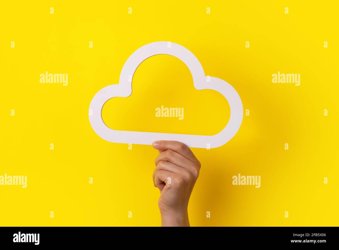 Cloud computing concept, hand holding cloud over yellow background ...