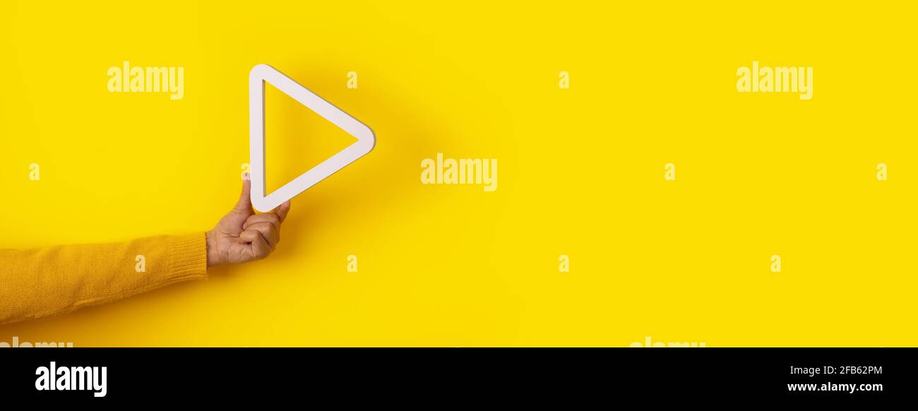 3d media play button in hand over yellow background, panoramic layout ...
