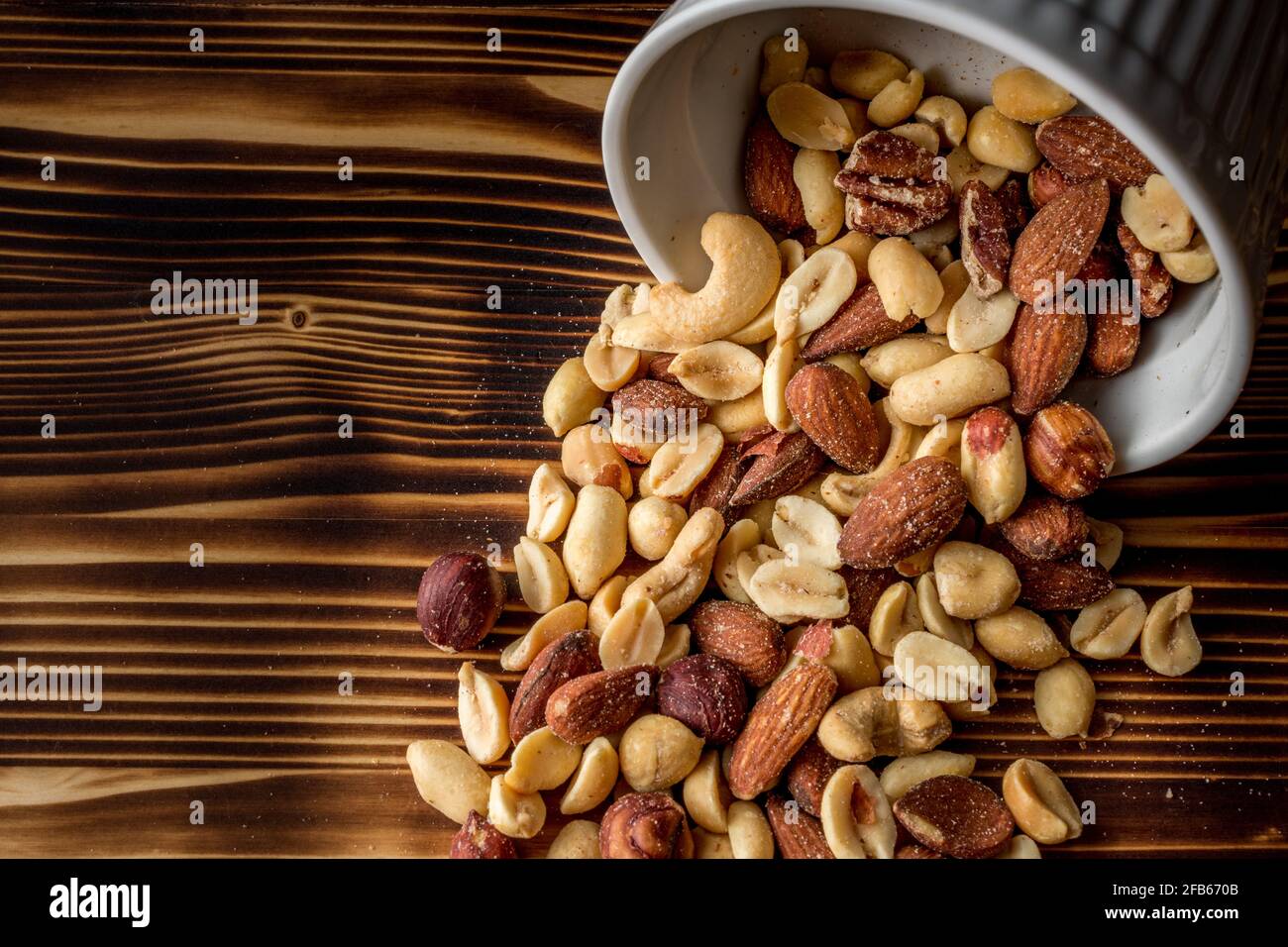 Nuts poured out on the wooden table from the bowl Stock Photo - Alamy