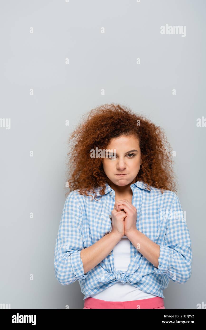 envy woman puffing cheeks while looking at camera on grey background ...