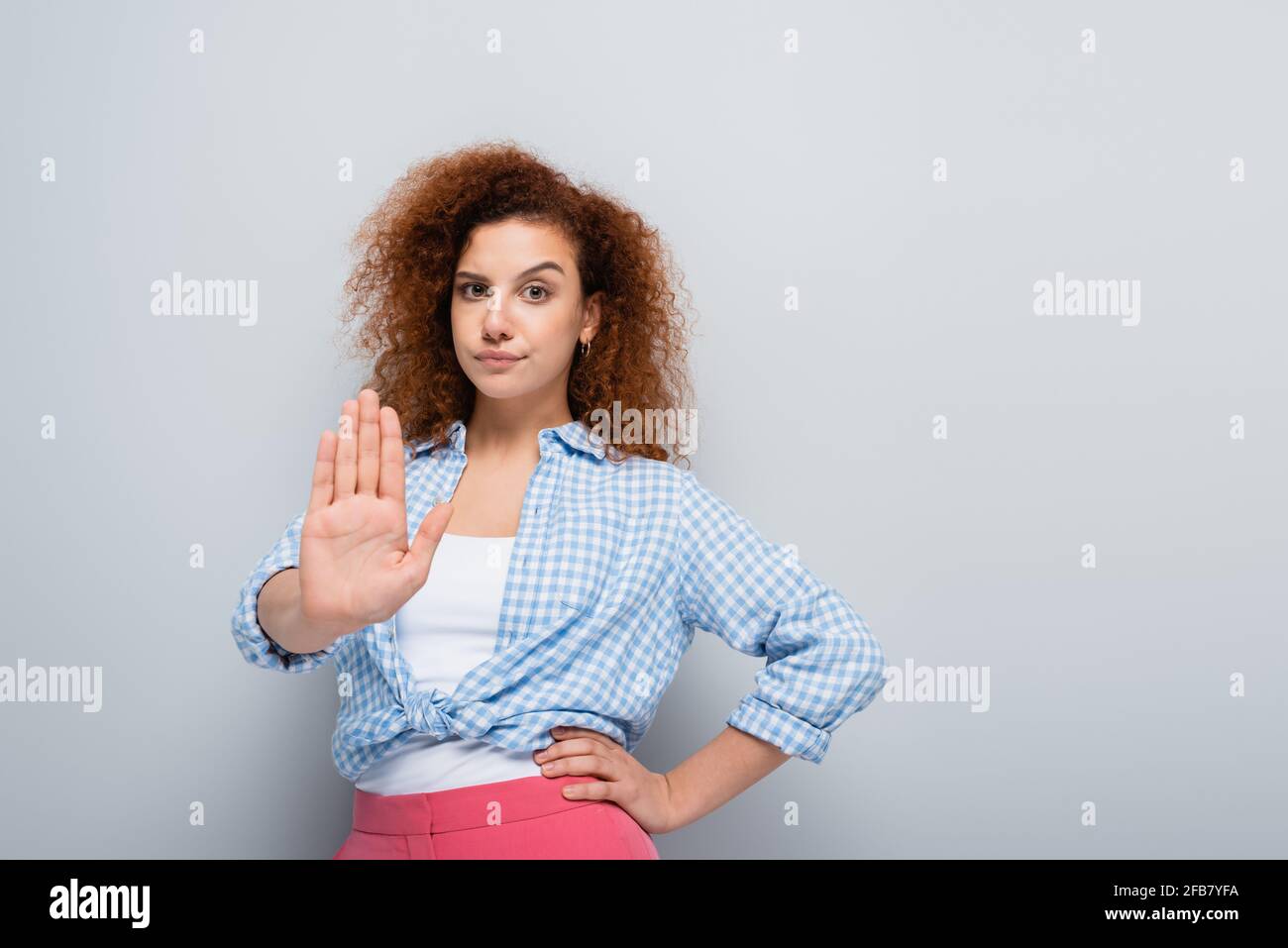 displeased woman showing refuse gesture while standing with hand on hip ...