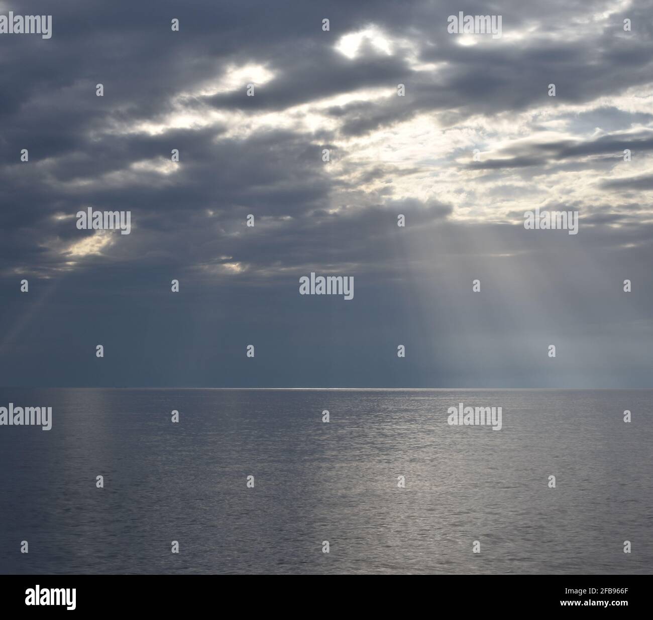 cloudy sky with sun rays filtering into the sea Stock Photo - Alamy