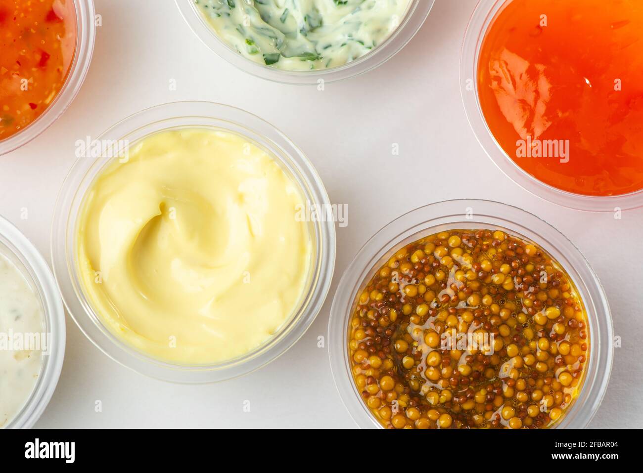 Top view on cups of various sauces and condiments on white background ...
