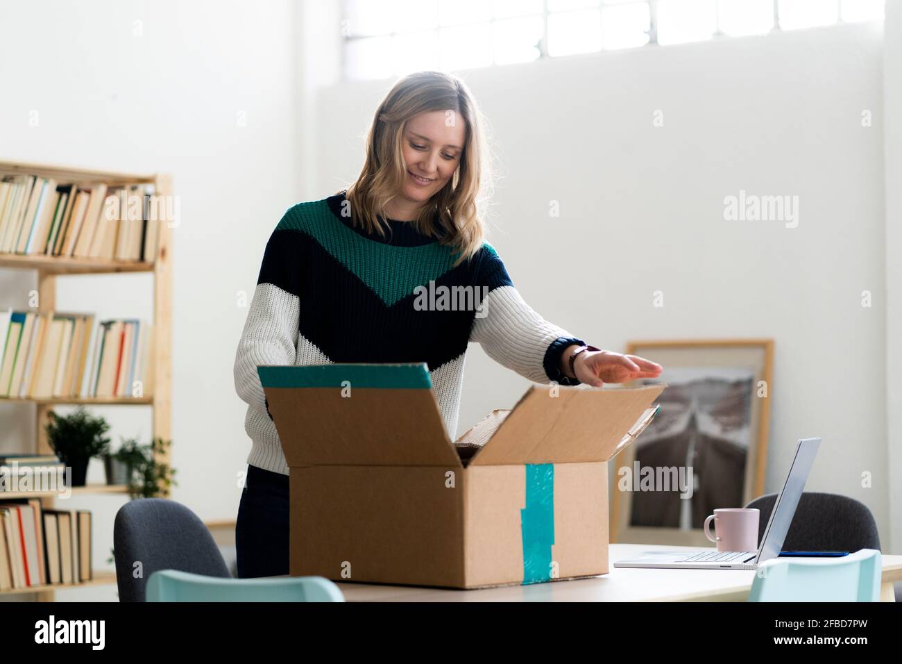 Mid adult woman opening cardboard box at home Stock Photo - Alamy