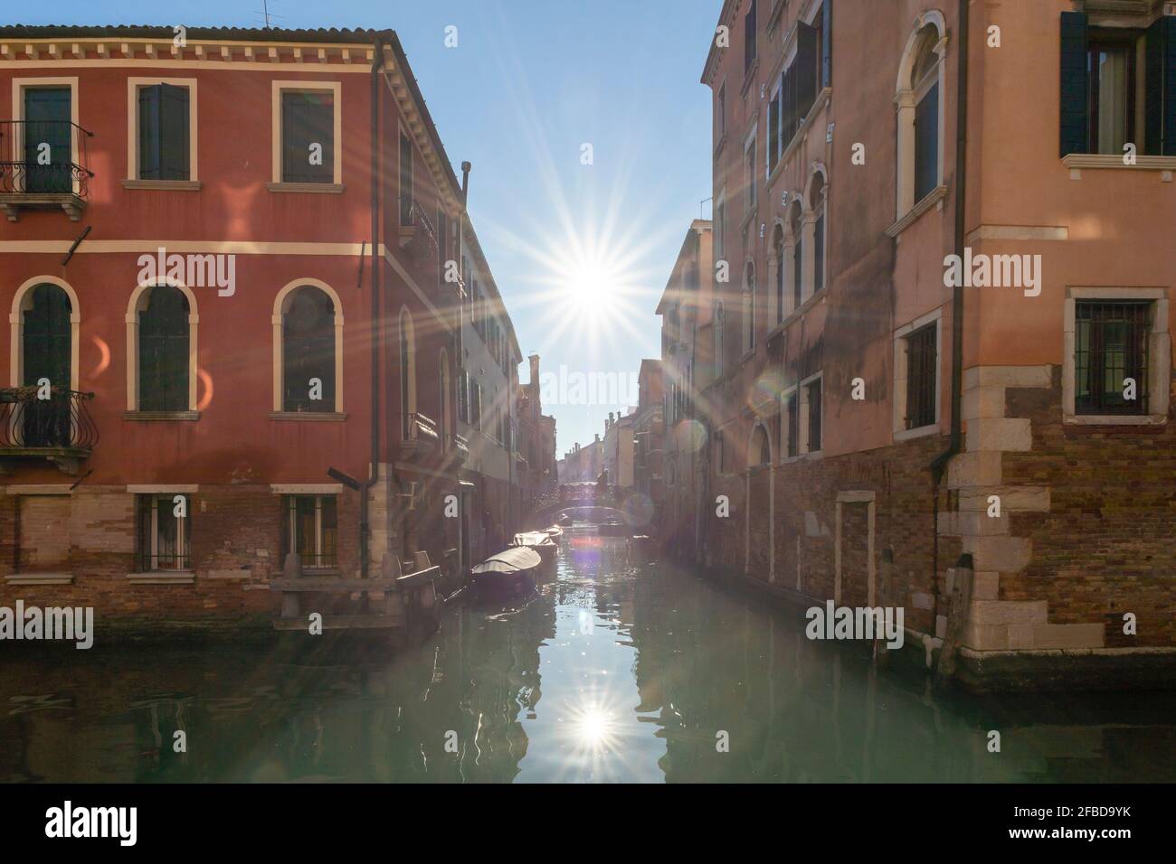 Italy, Veneto, Venice, Sun setting between rows of houses standing ...