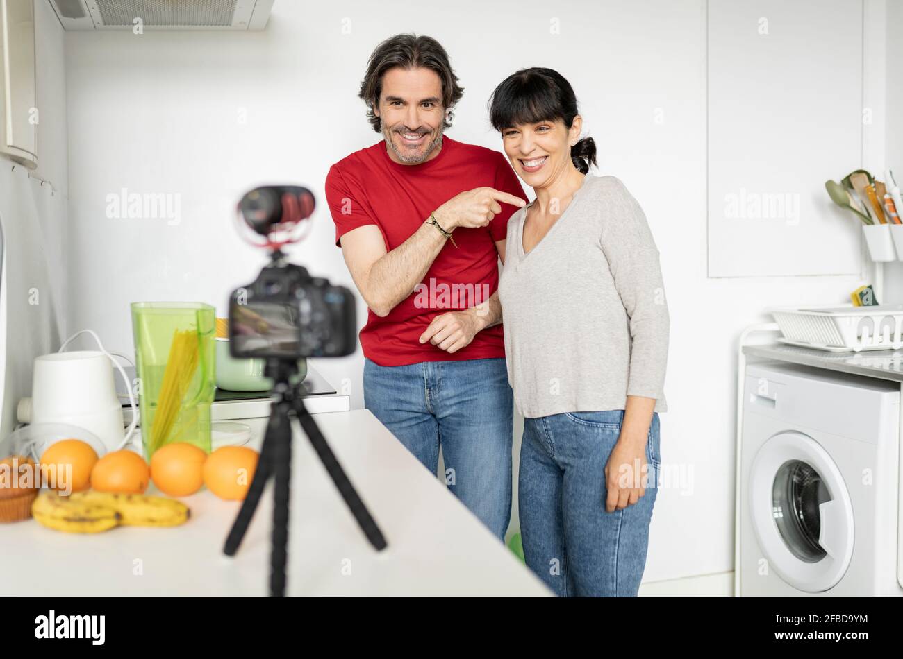 Man pointing at woman while vlogging in kitchen at home Stock Photo - Alamy