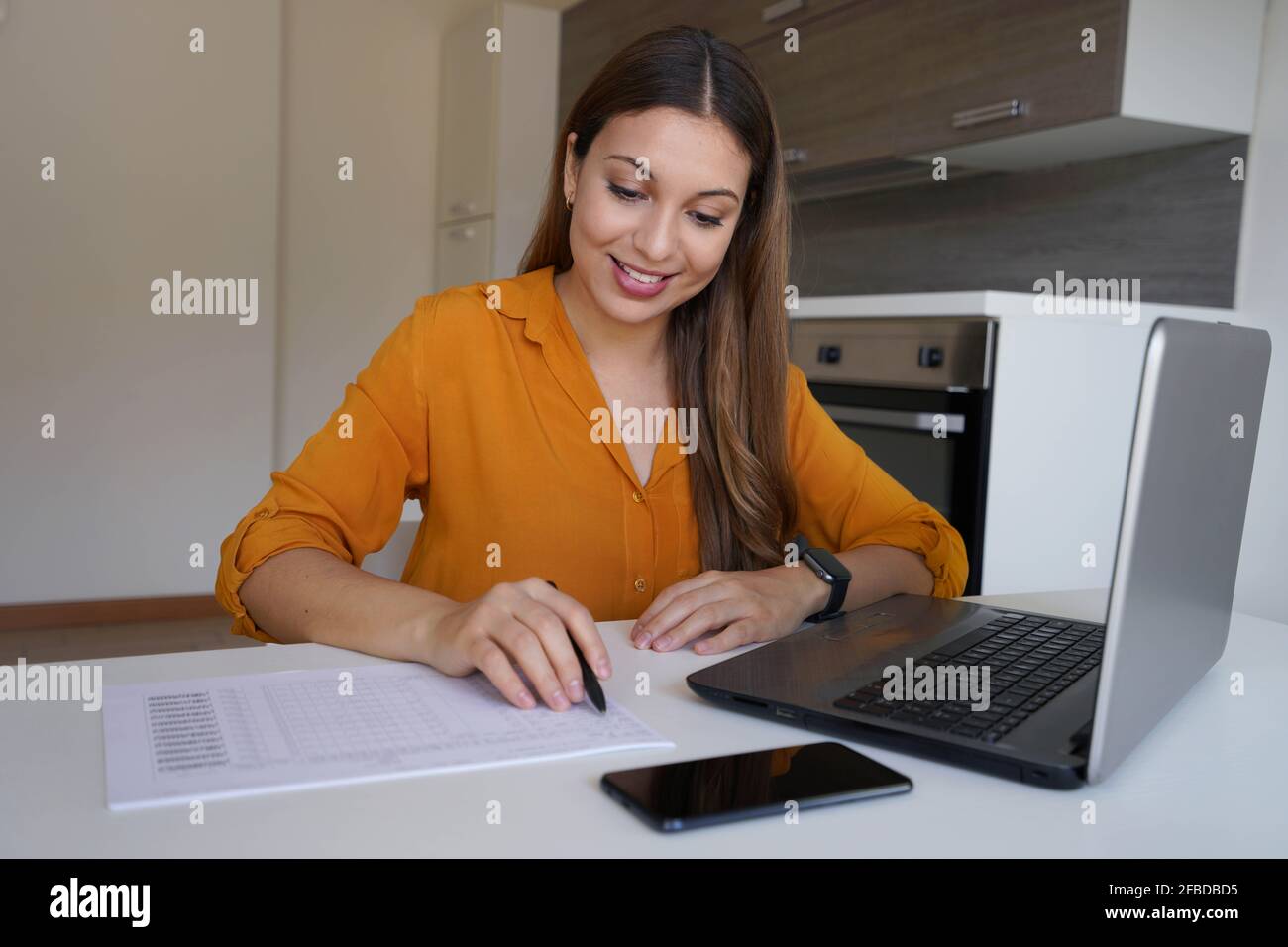 Beautiful woman working at home filling out and checking documents ...
