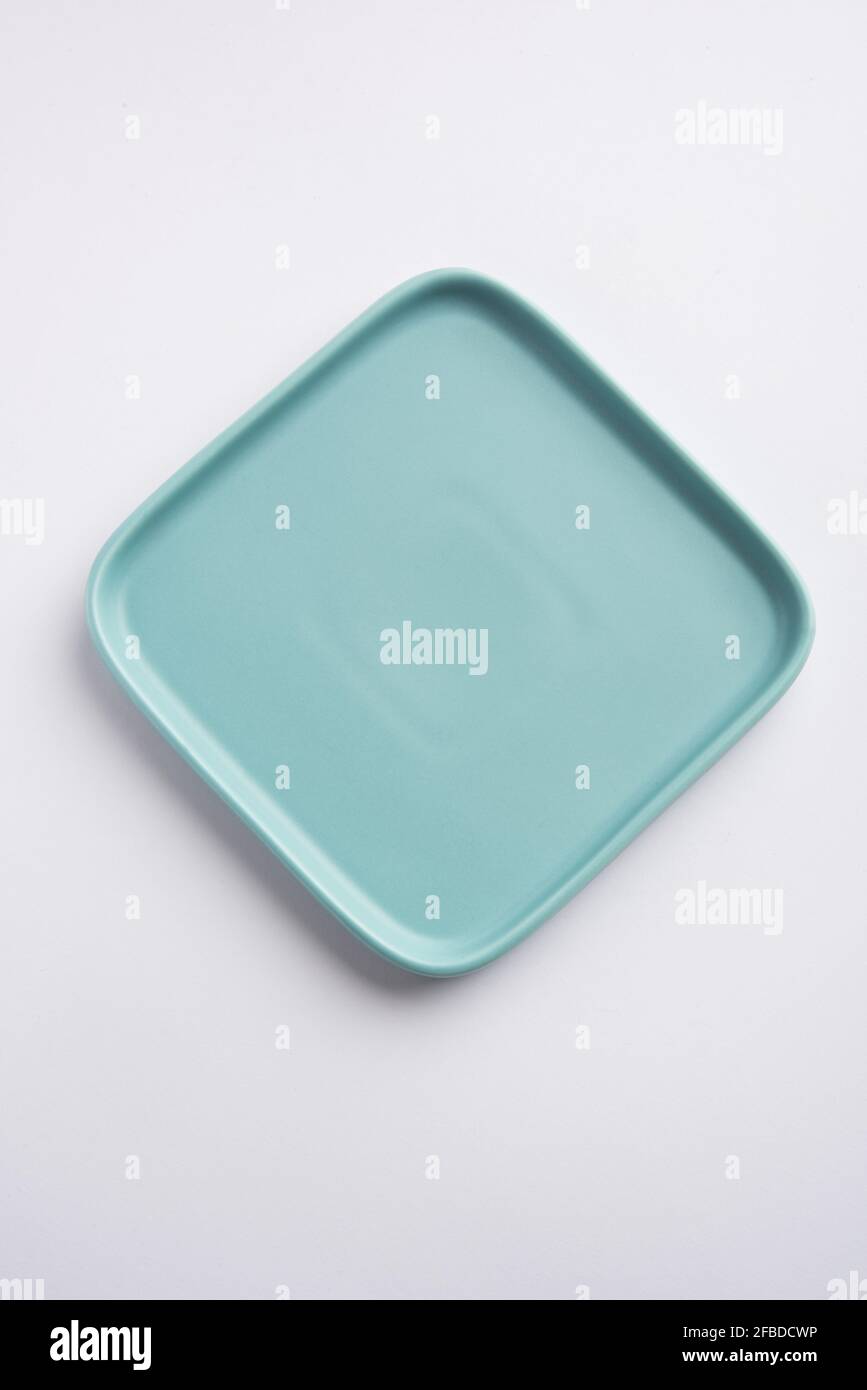 Empty light green or blue ceramic square plate isolated on white ...