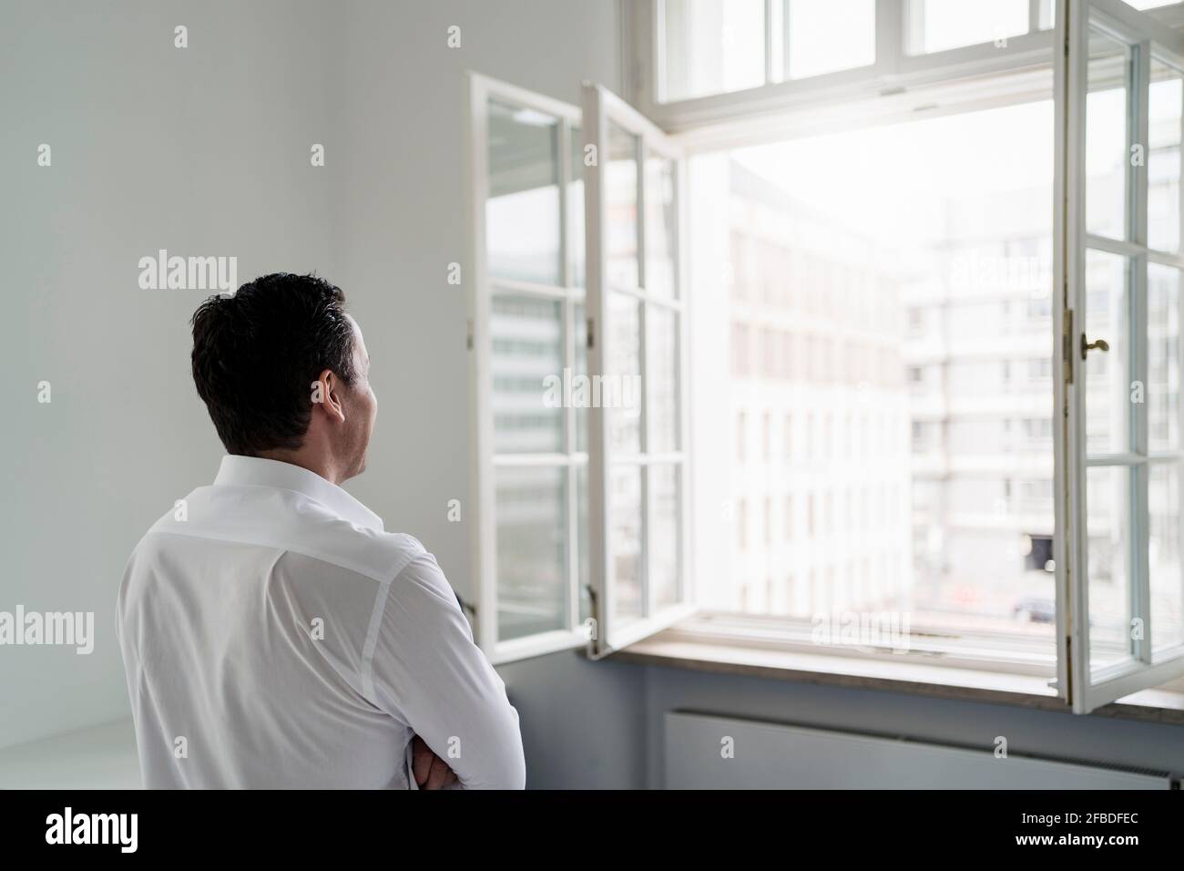 Male professional looking through window at office Stock Photo - Alamy