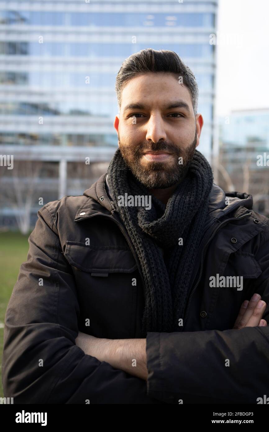 Bearded man with arms crossed standing against building Stock Photo - Alamy