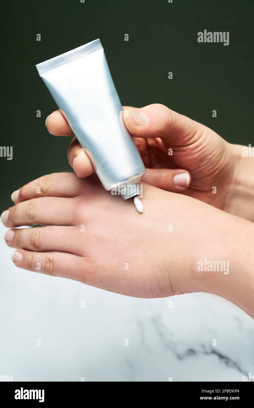Woman taking hand cream over green background Stock Photo - Alamy
