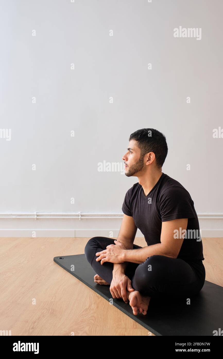 Thoughtful man sitting on mat near wall in exercise room Stock Photo ...