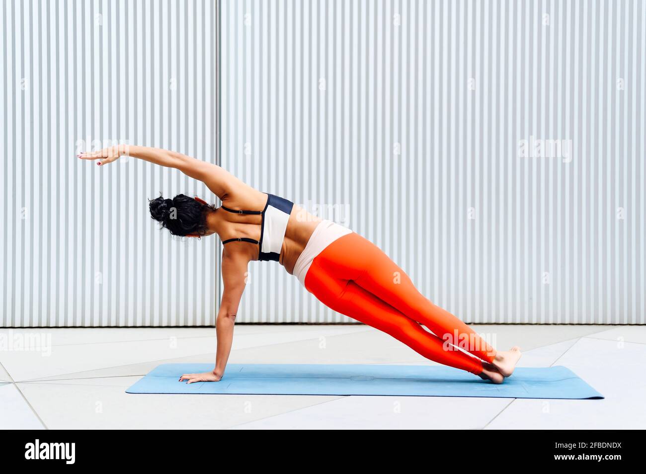 Female sportswoman doing side plank pose in front of wall Stock Photo ...