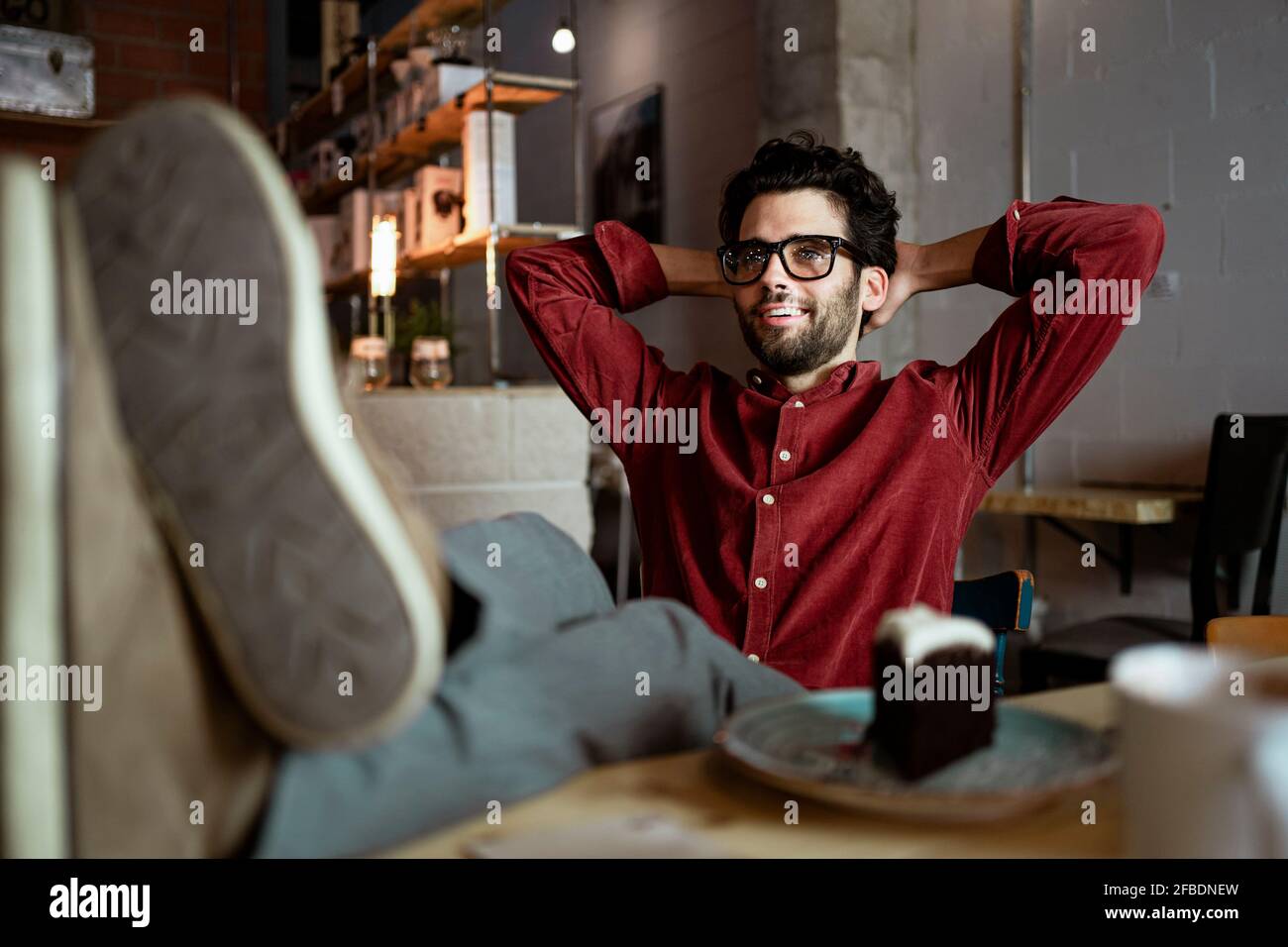 Businessman resting leg on table while day dreaming in illuminated cafe ...
