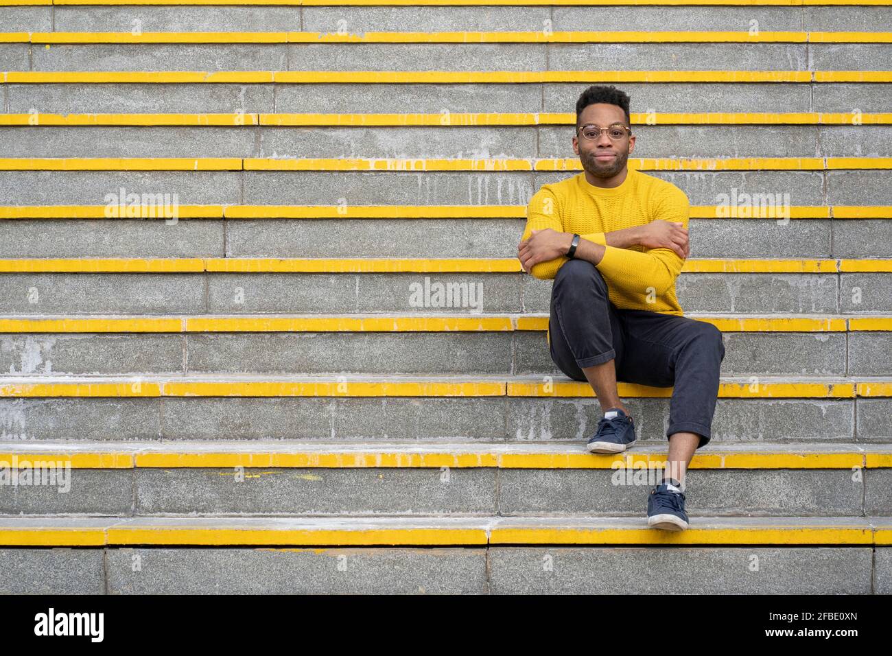 Man with arms crossed sitting on staircase Stock Photo - Alamy