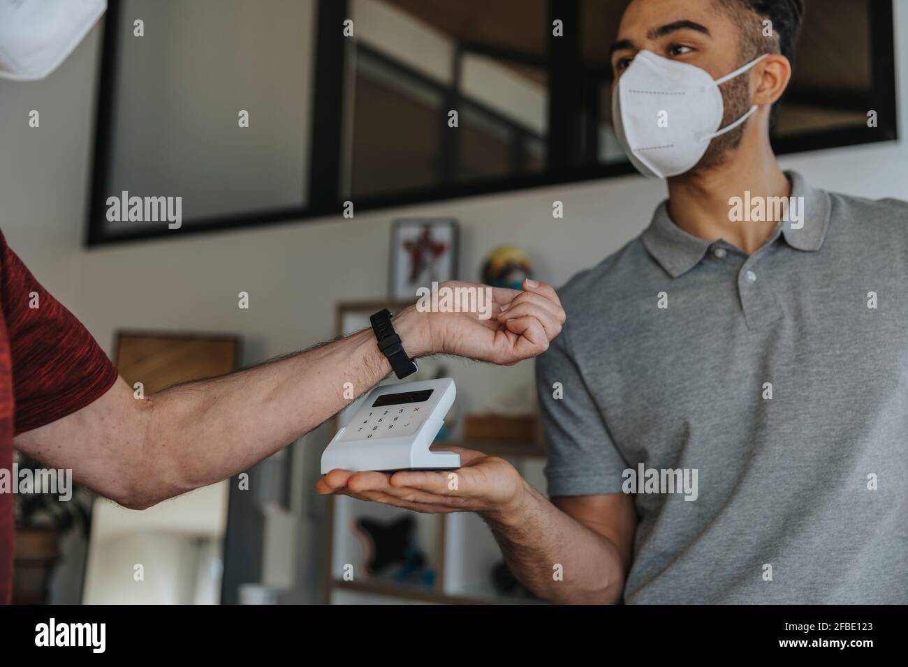 Physiotherapist holding credit card reader while patient using smart ...