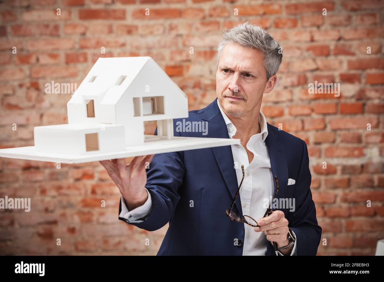 Male entrepreneur with eyeglasses looking at architectural model in ...