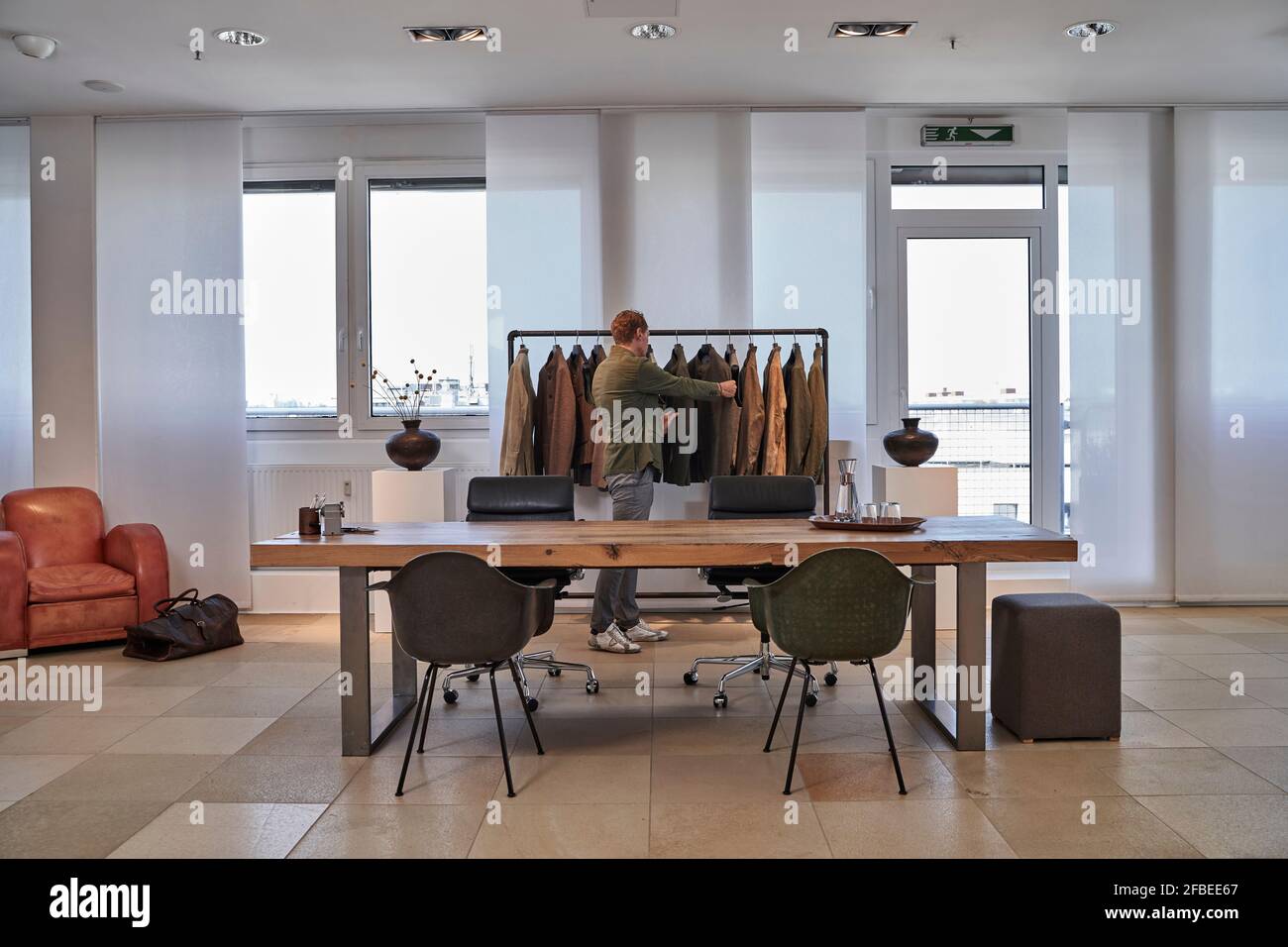 Male customer looking clothes hanging on rack at clothing studio Stock ...