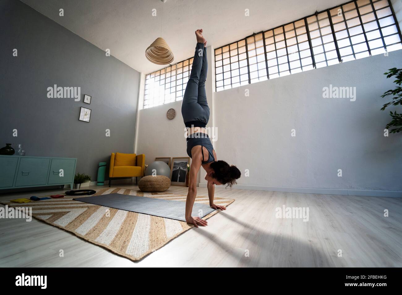 Young woman balancing on hands in living room Stock Photo - Alamy