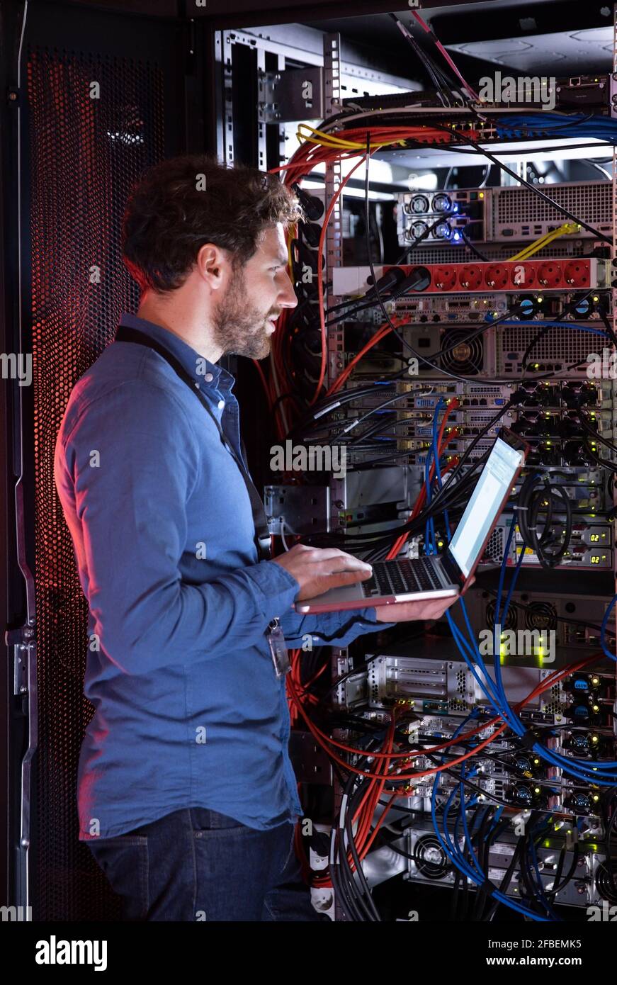 Smiling male IT professional looking away while holding laptop in ...