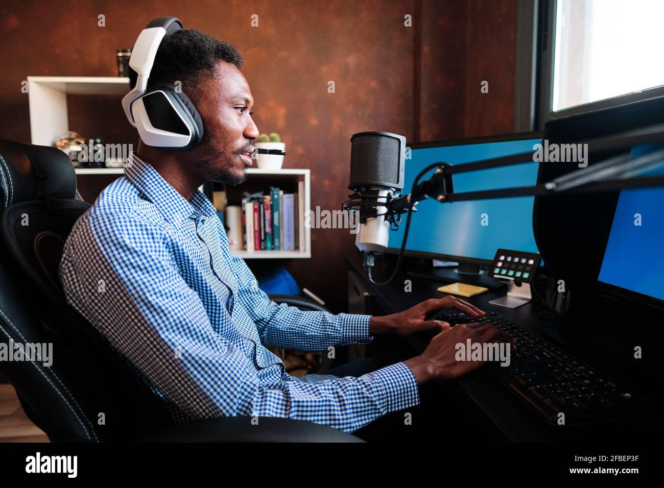 Male influencer talking through microphone while using computer during ...