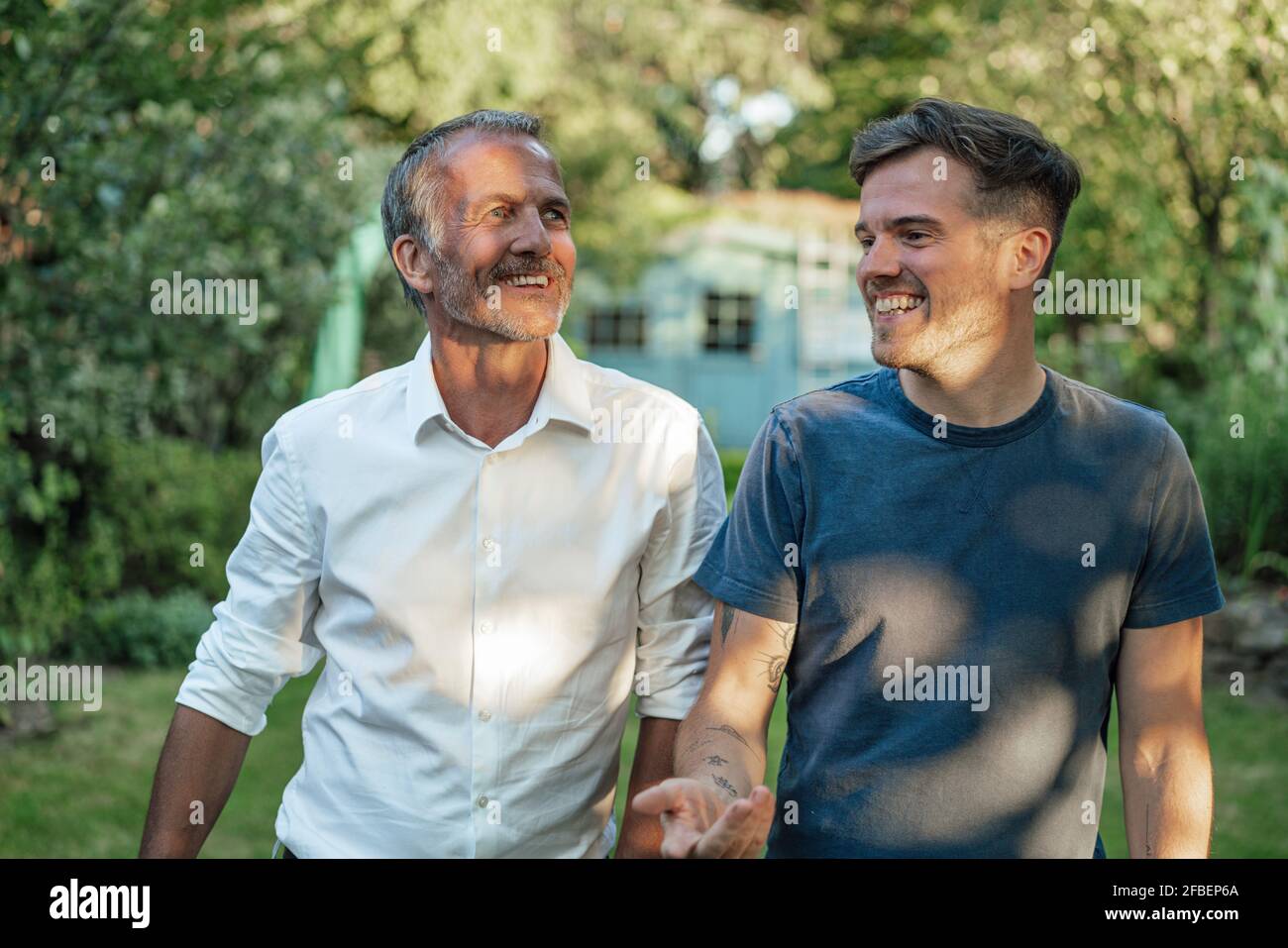 Smiling son discussing with father looking away in garden Stock Photo ...