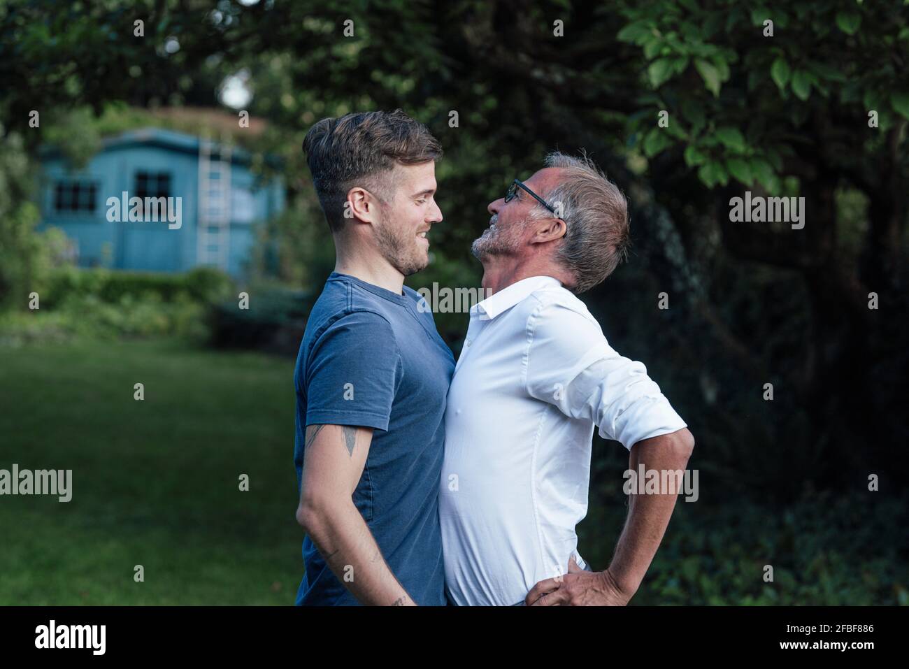 Father and son giving chest bump while standing in backyard Stock Photo ...