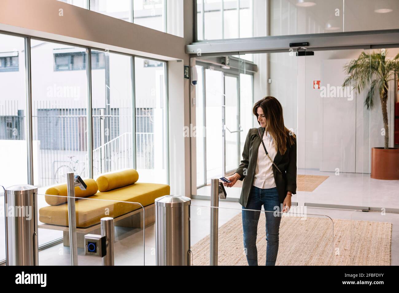 Mid adult woman showing ID card at reader while entering office Stock ...