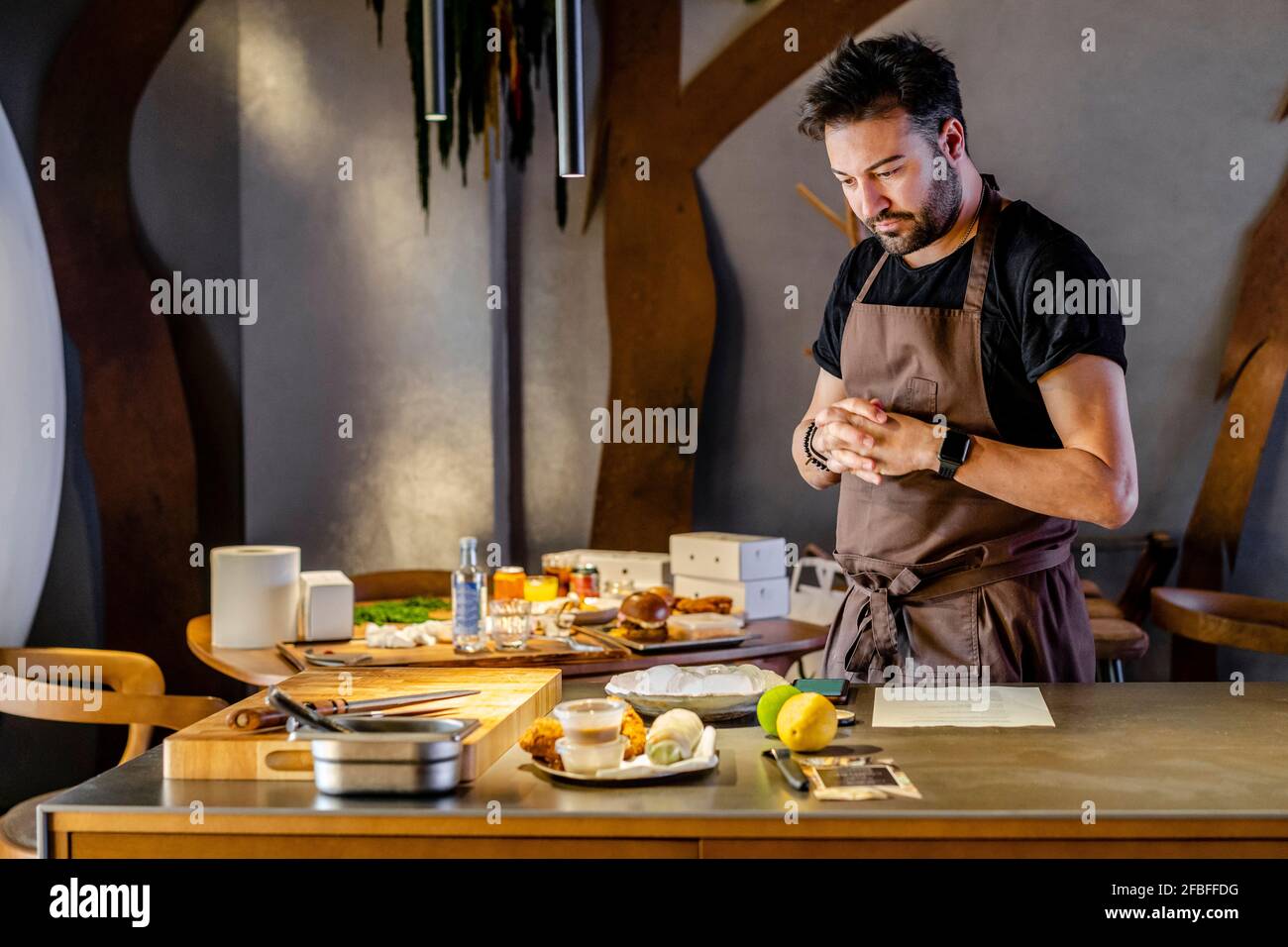 Thoughtful male chef looking at food in commercial kitchen Stock Photo ...