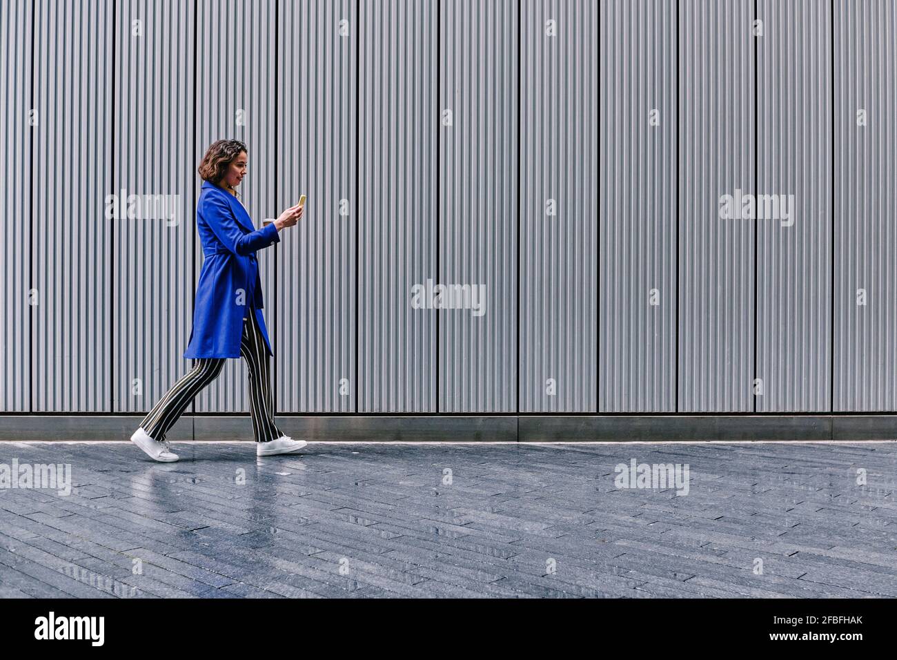 Walking with smartphone side coat hi-res stock photography and images ...