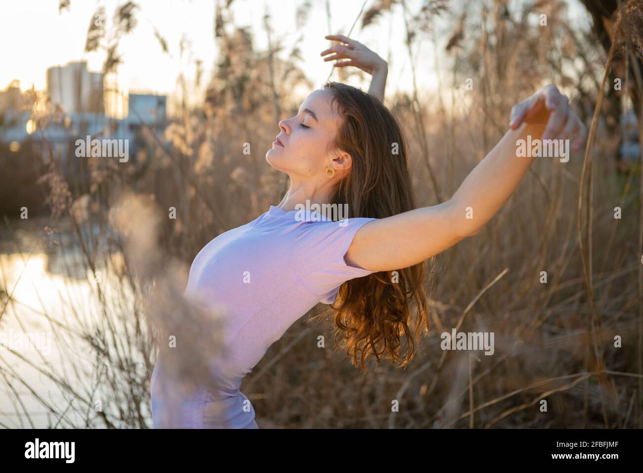 Beautiful young woman with arms raised dancing in nature Stock Photo ...