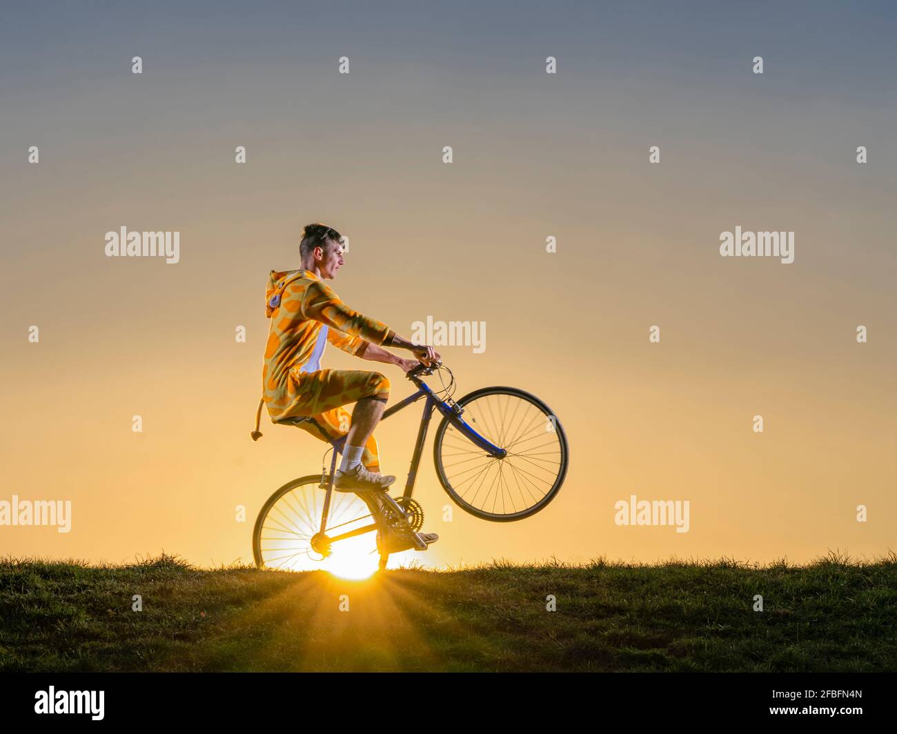 Young man doing bicycle stunts during sunset Stock Photo - Alamy