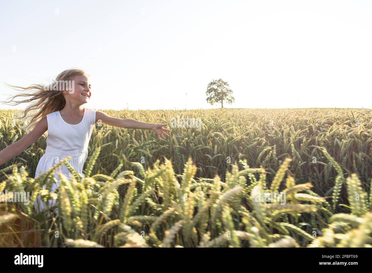 Happy girl running on green field during sunset Stock Photo - Alamy