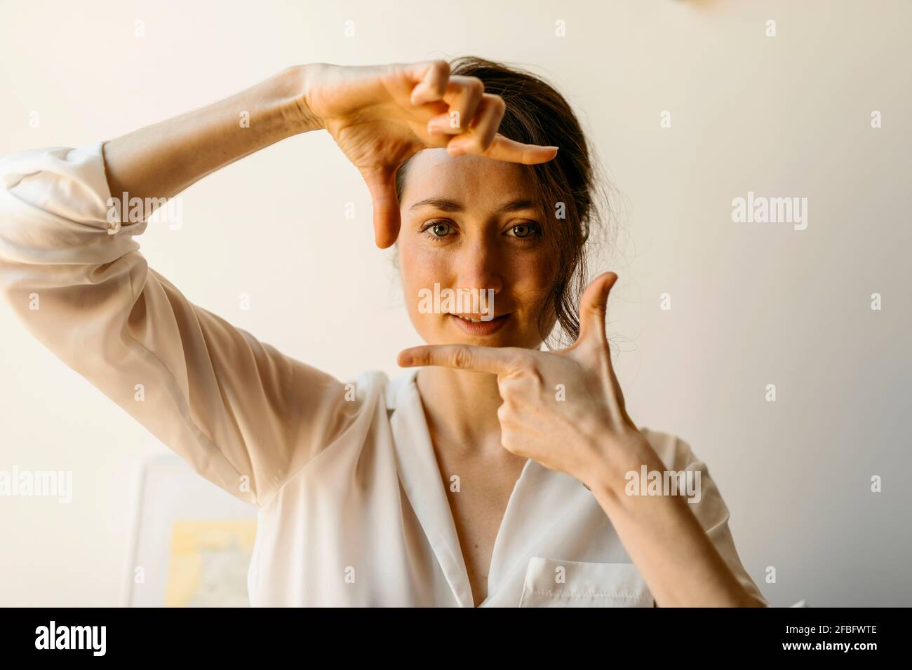 Beautiful woman making finger frame at home Stock Photo - Alamy