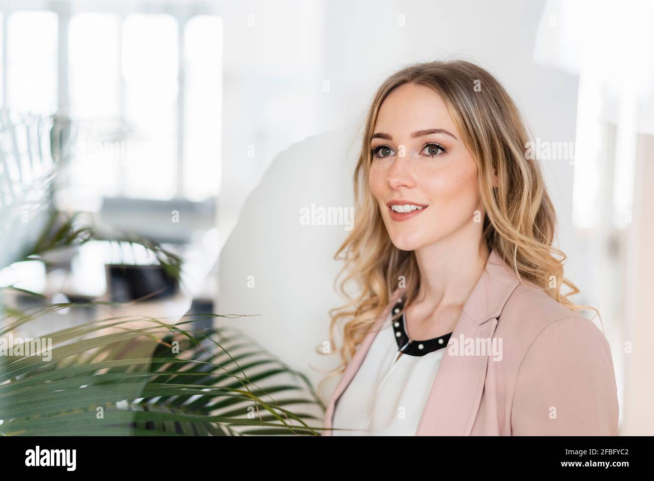 Contented businesswoman day dreaming seen through glass at office Stock ...