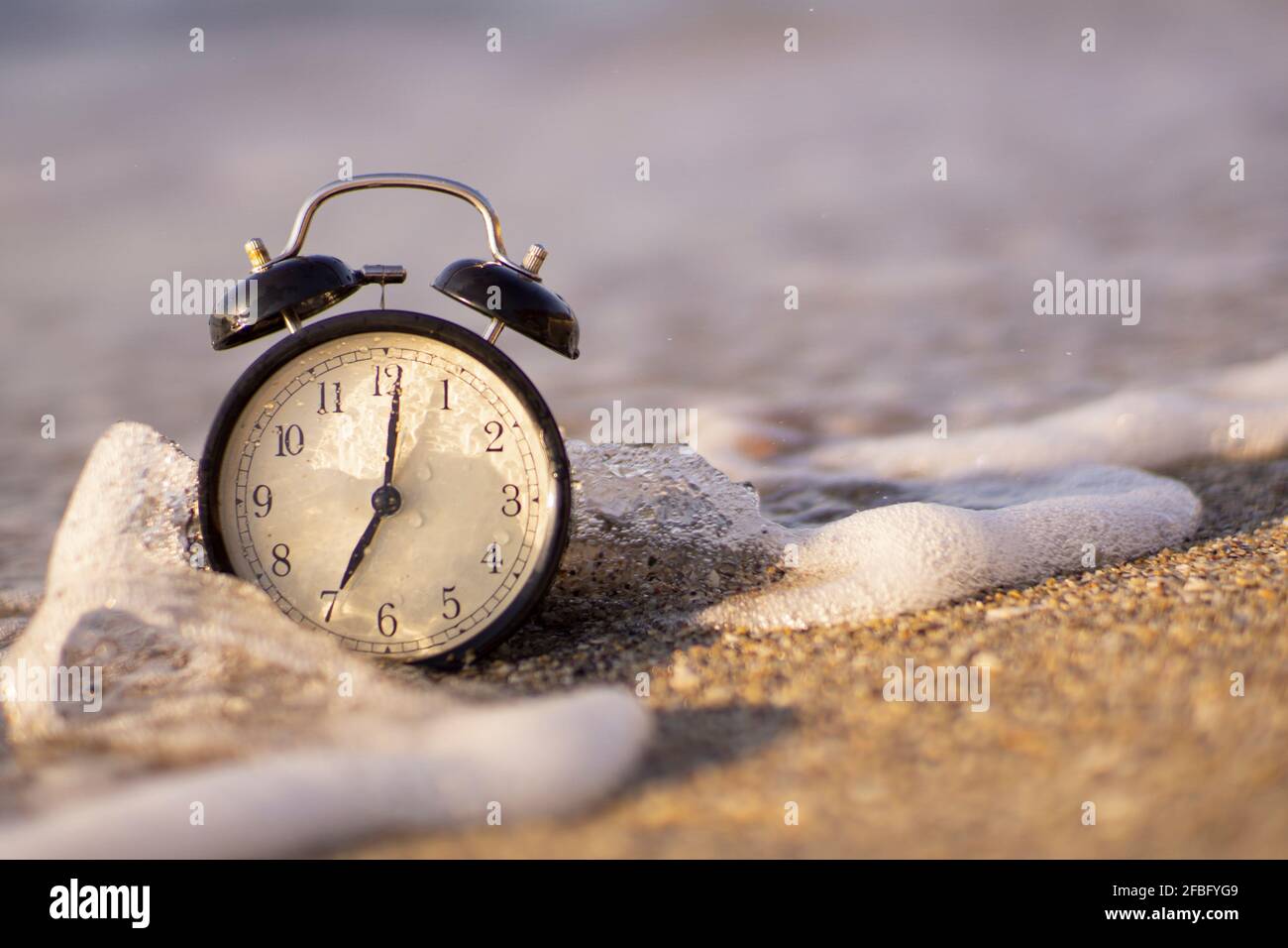 Alarm clock splashing in the beach water Stock Photo - Alamy
