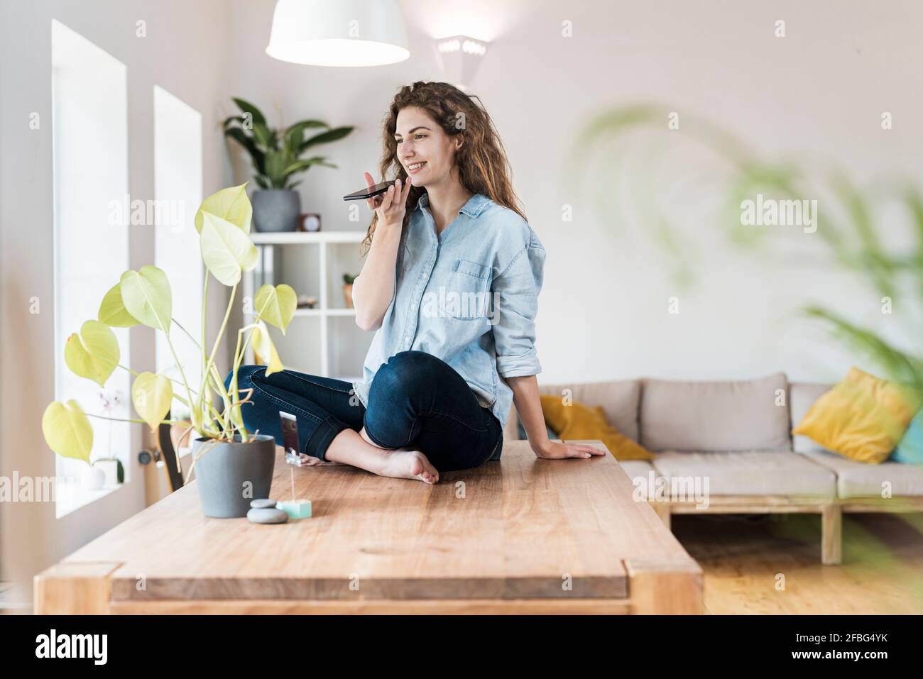Smiling woman with crossed legs talking on mobile phone at home Stock ...