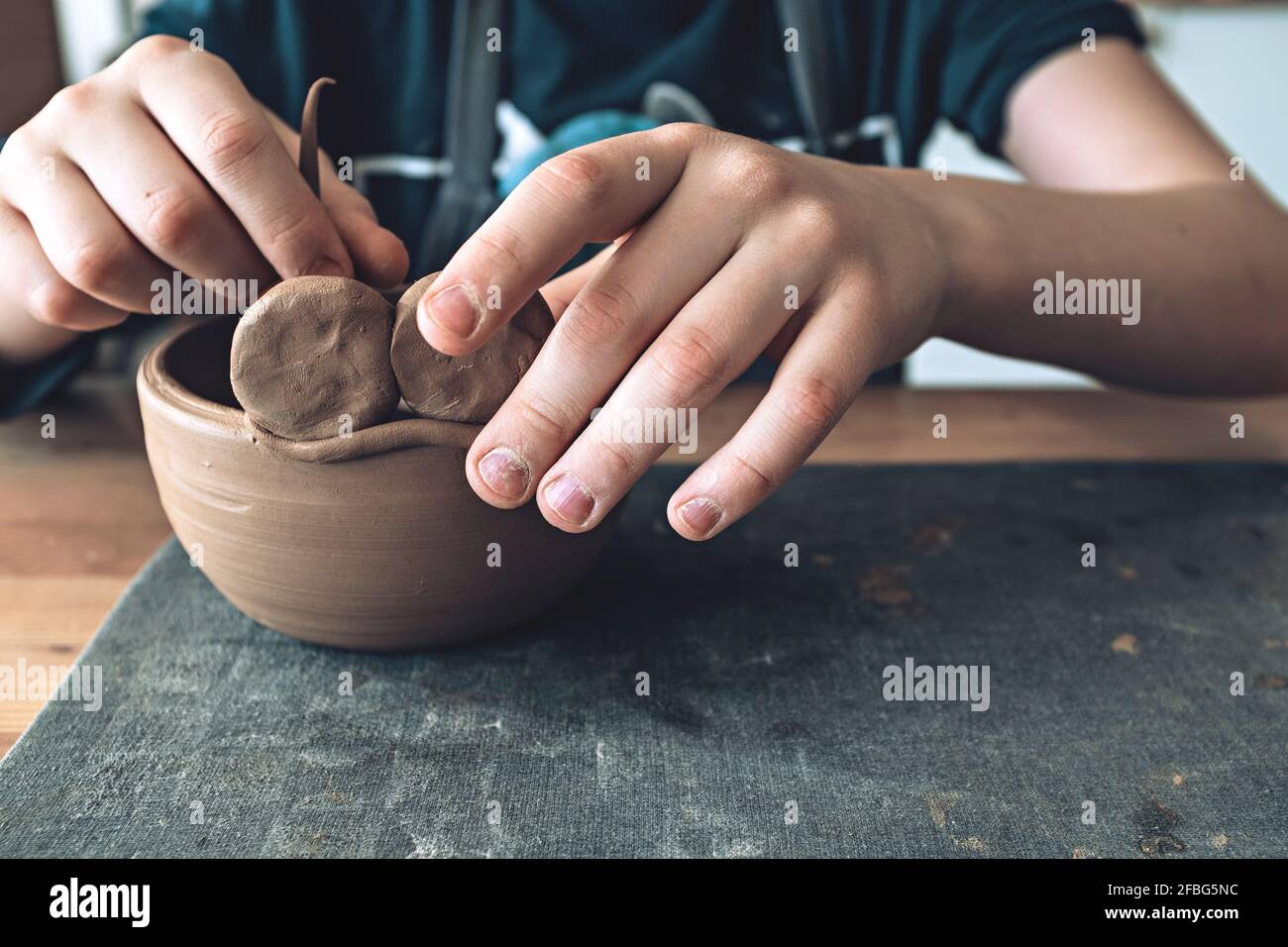 Hands of a young artist, modeling a clay bowl in art studio ...