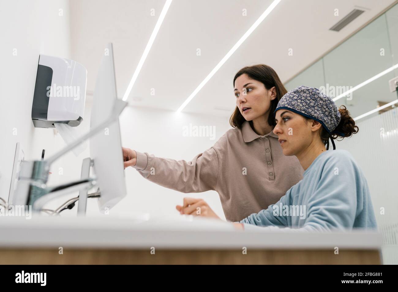 Dentist using computer while working with colleague at office Stock ...