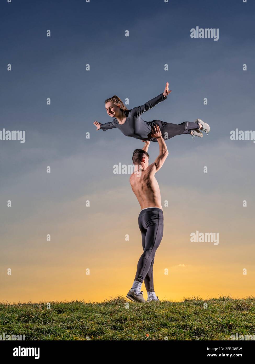 Man lifting woman while doing acrobats during sunset Stock Photo - Alamy
