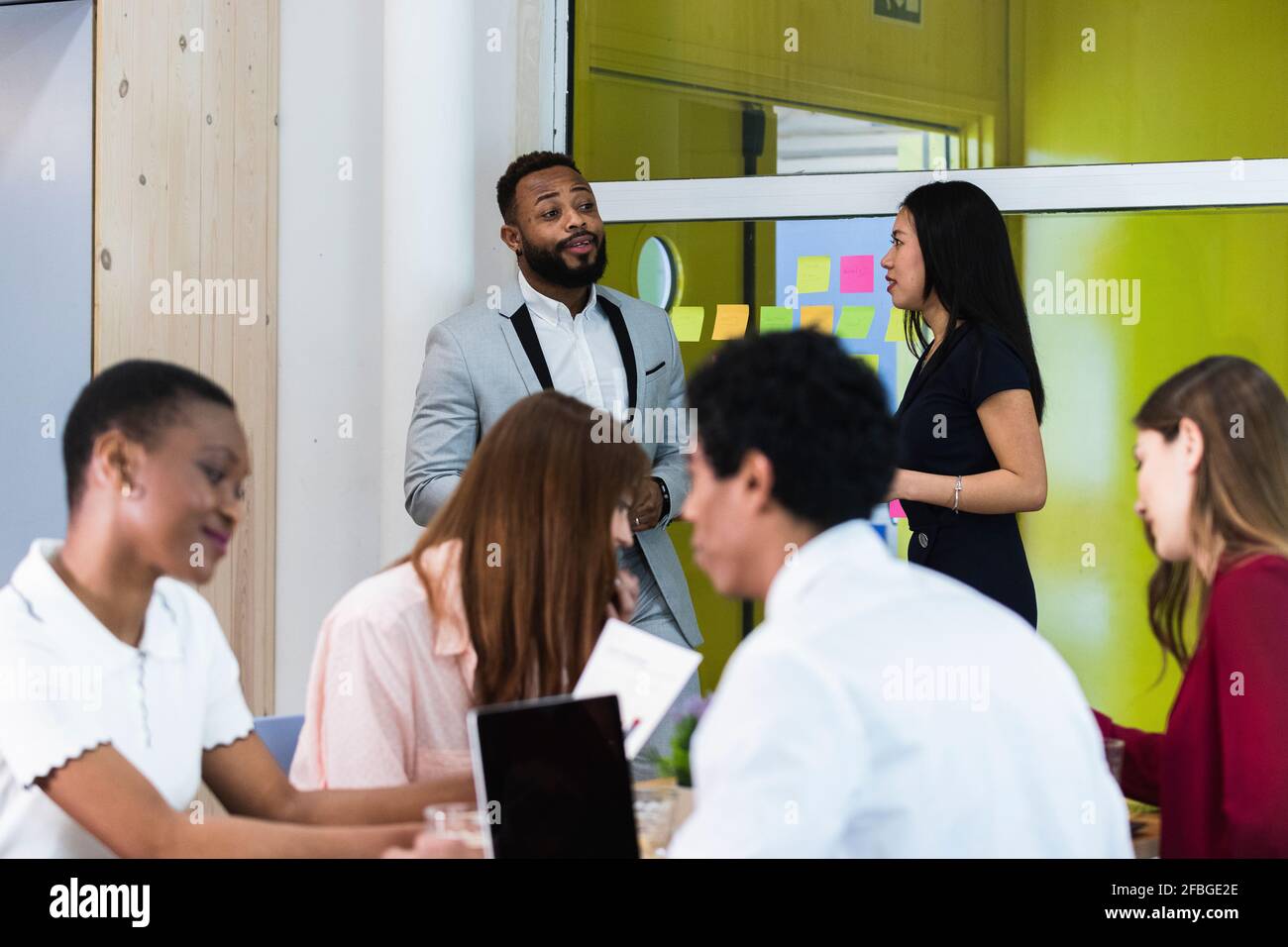 Business people having discussion with colleagues working in meeting ...
