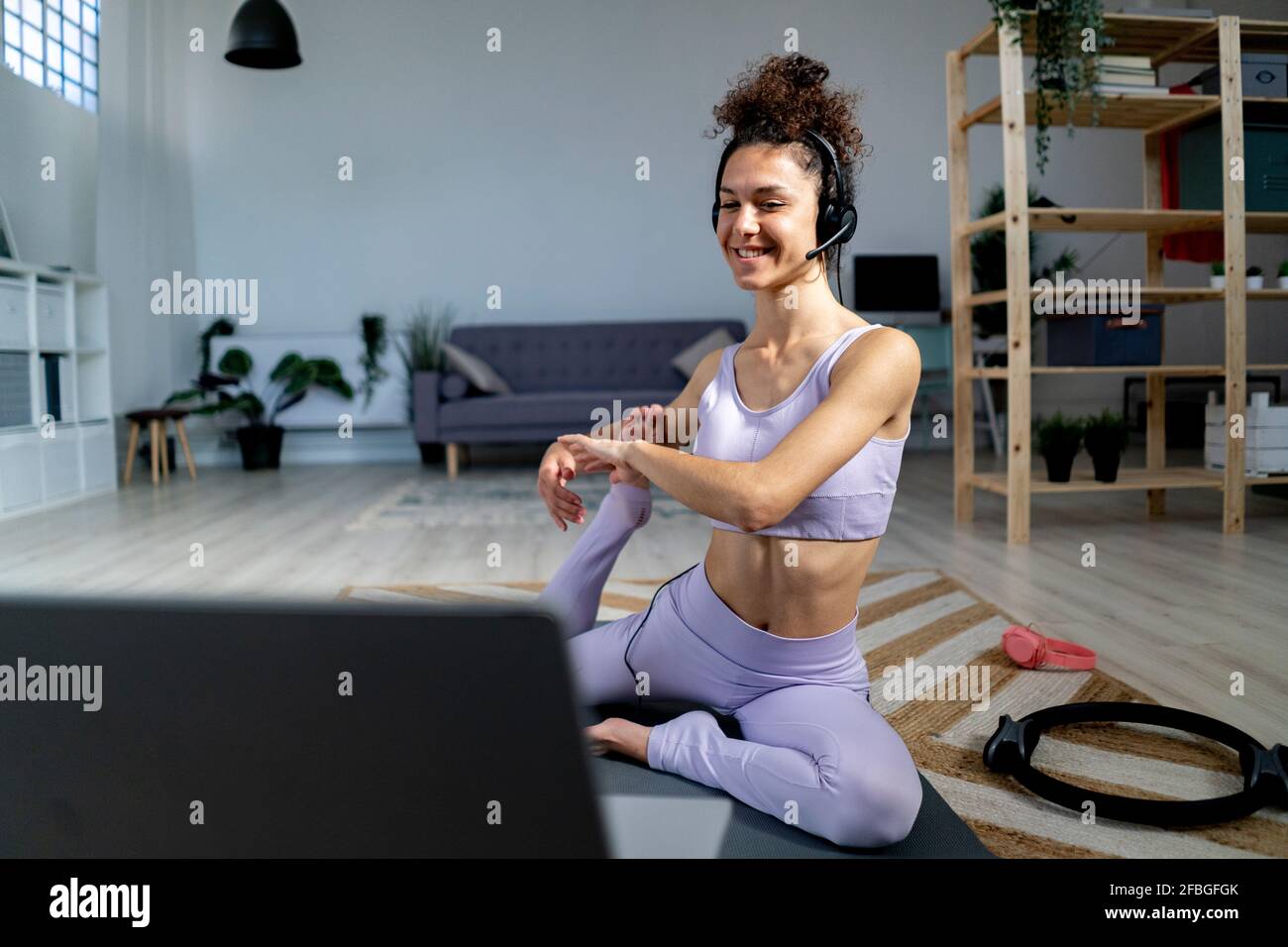 Smiling yoga influencer with headphones doing mermaid pose while ...