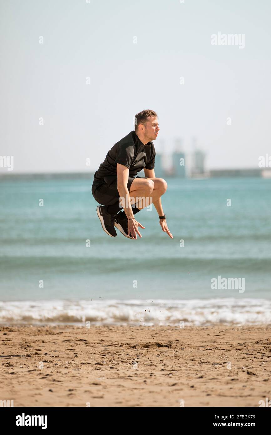 Man jumping at beach during sunny day Stock Photo - Alamy