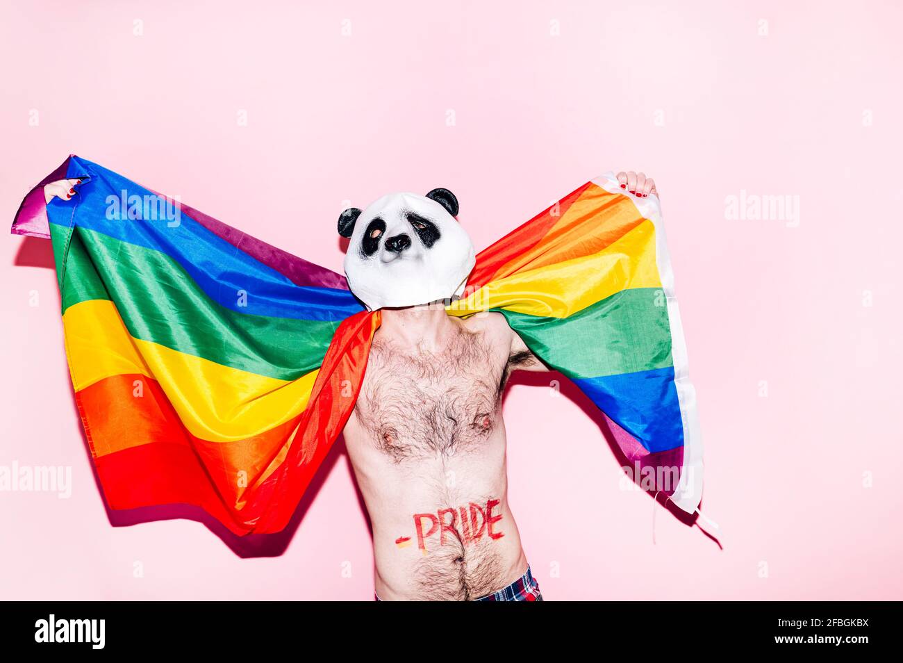 Covered face of gay man with rainbow flag flexing biceps standing ...