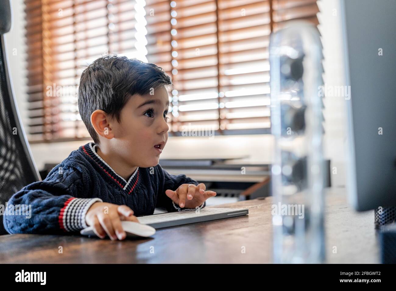 Curious boy using computer at home Stock Photo - Alamy