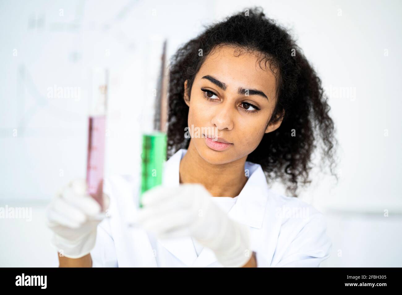 Female chemist examining liquid in test tubes while working in ...