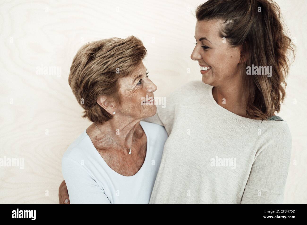 Caring granddaughter hugging grandmother against wall Stock Photo - Alamy
