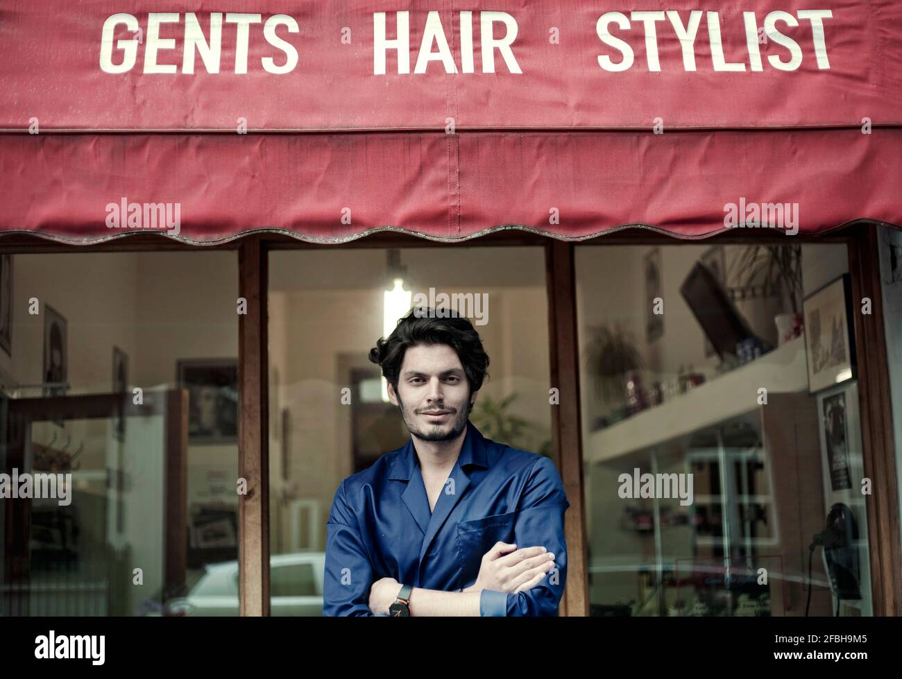 Portrait of handsome barber standing in front of barber shop with ...