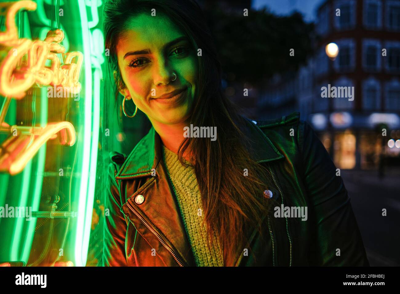 Beautiful woman with jacket standing by illuminated light Stock Photo ...