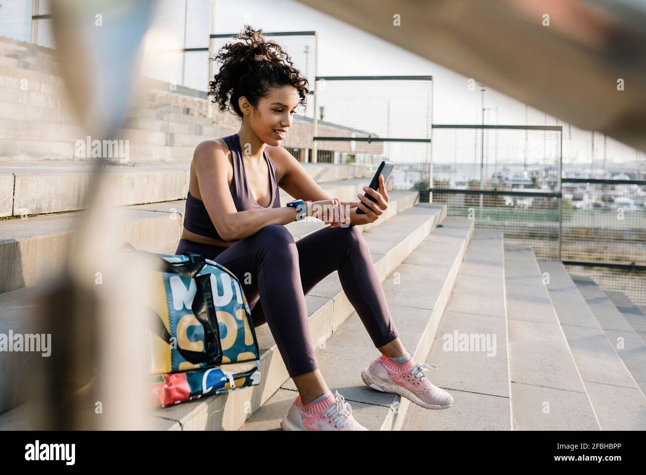 Female athlete using mobile phone while sitting on staircase Stock ...